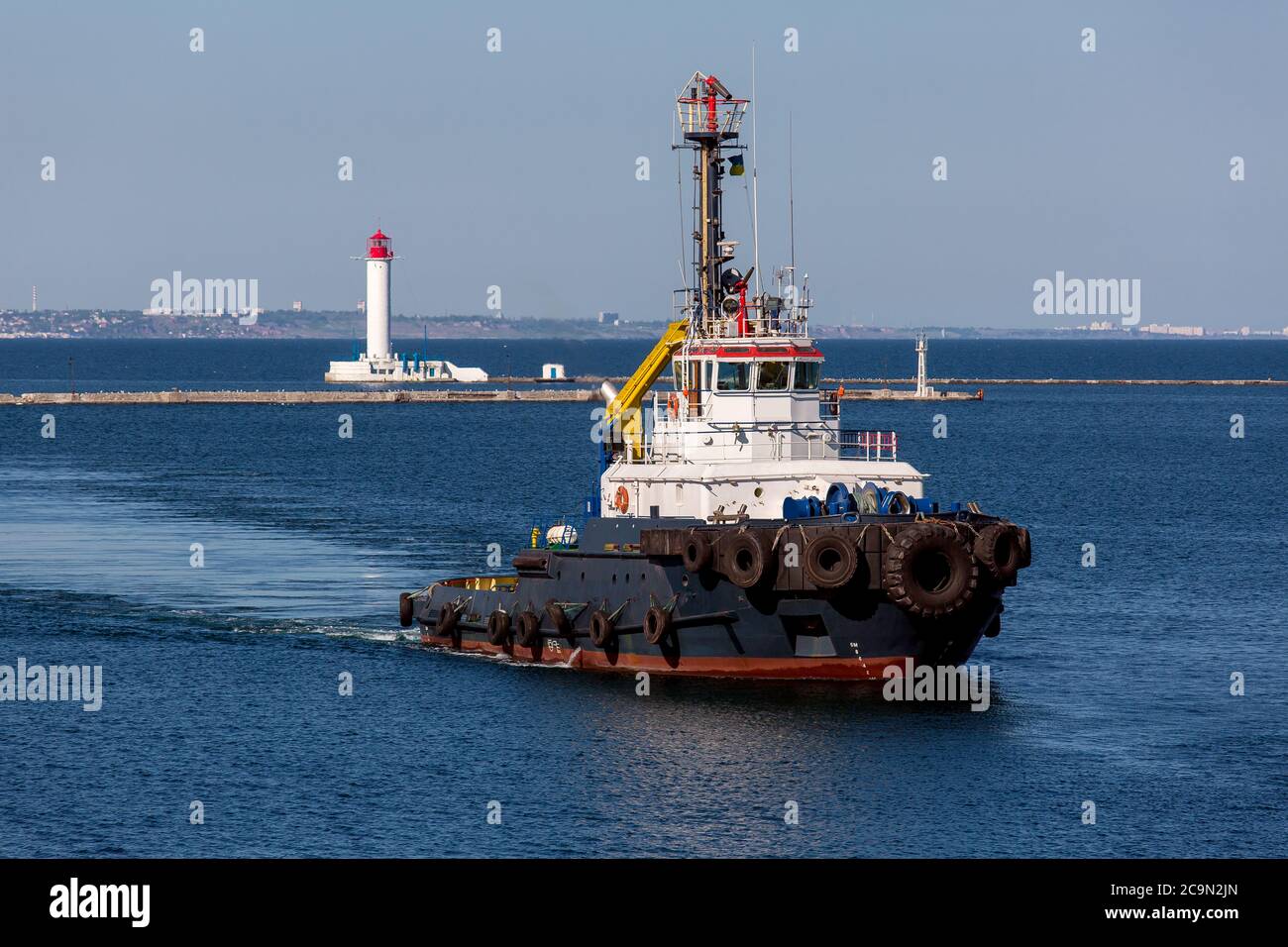 tugboat with fire trunk on maneuvers at sea, behind beacon Stock Photo ...