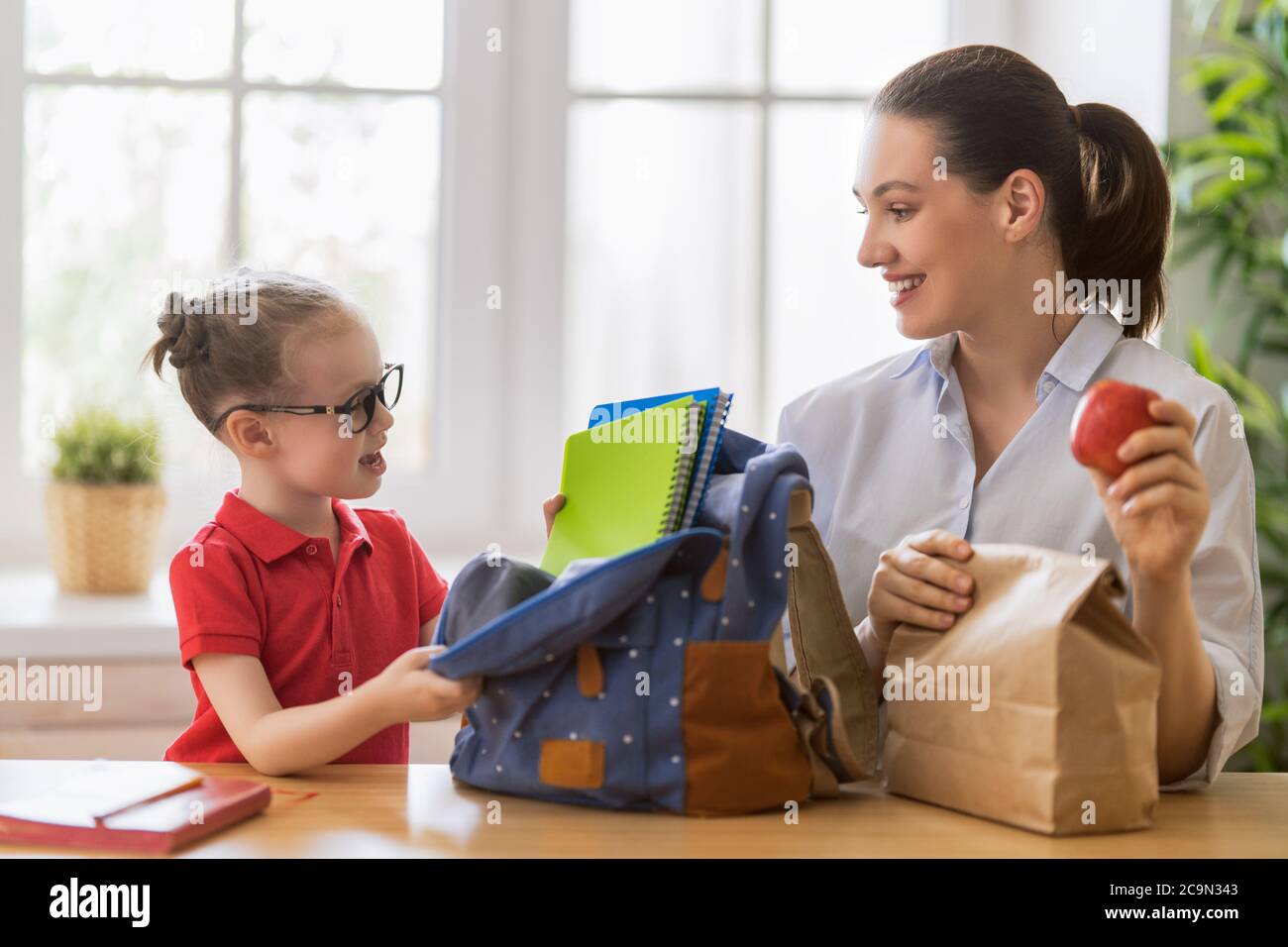 Happy family preparing for school. Little girl with mother putting ...
