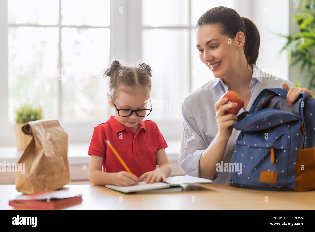 Happy family preparing for school. Little girl with mother putting ...