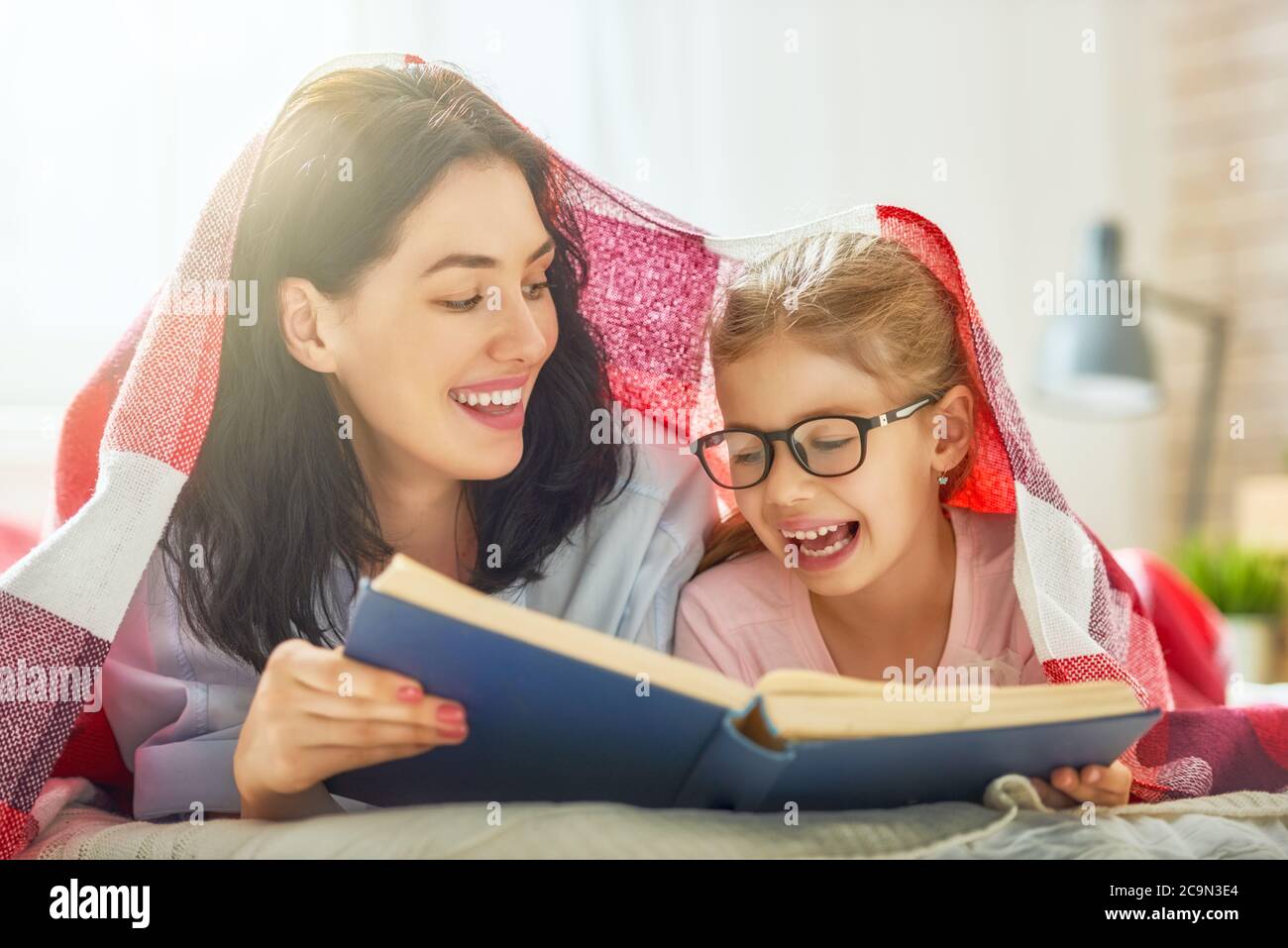Pretty young mother reading a book to her daughter. Family holiday and ...