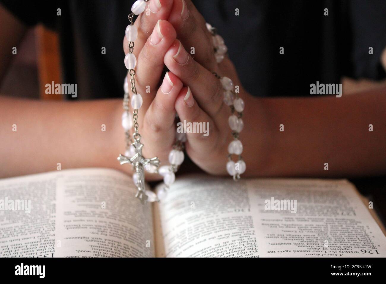 catholic praying hands with bible and rosary beads background with copy ...