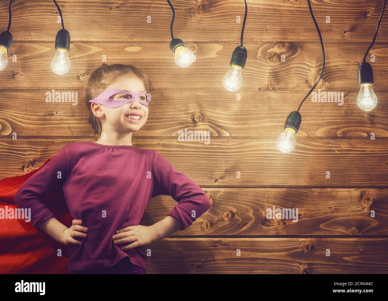 Little child girl plays superhero. Child on the background of wooden ...