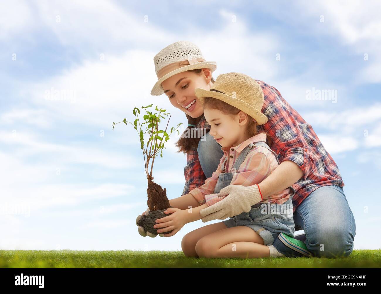 Mom and her child girl plant sapling tree. Spring concept, nature and ...