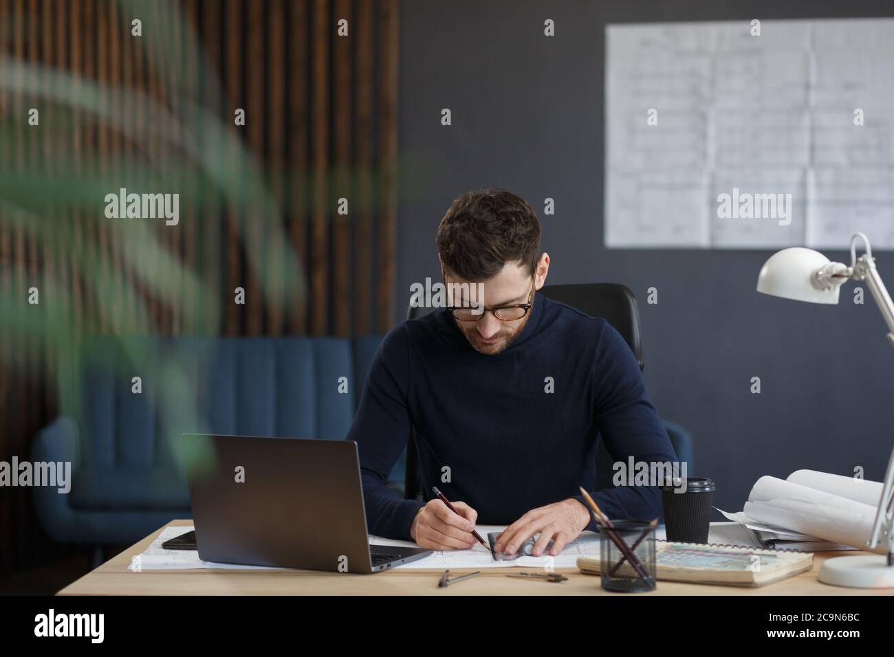 Architect working in office with laptop. Engineer thinks over ...