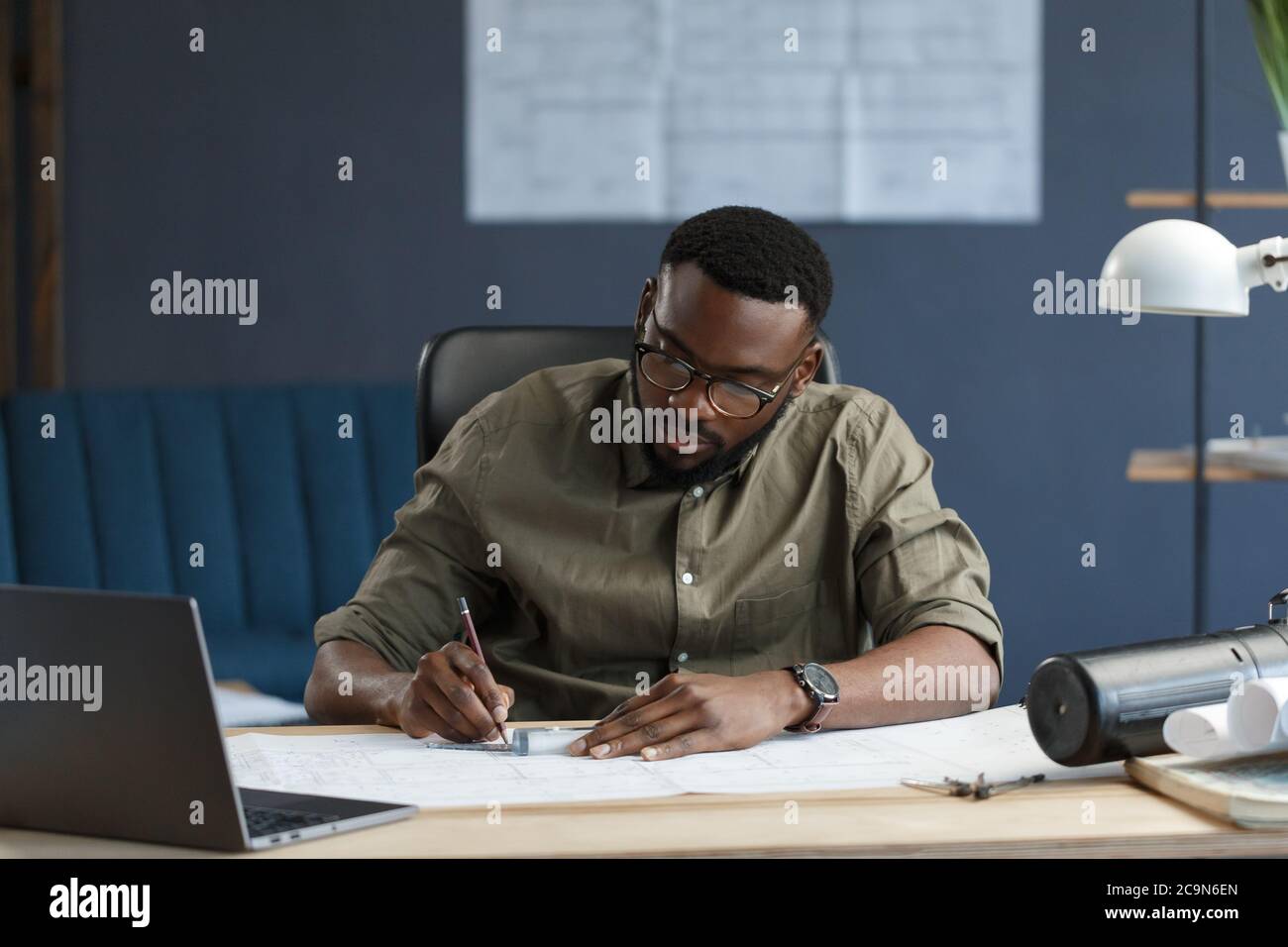 Afro-American architect working in office with blueprints.Engineer ...