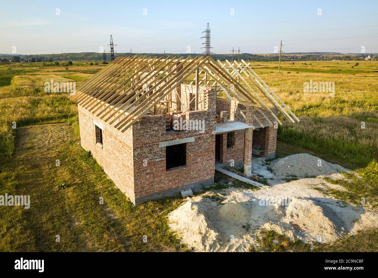 Unfinished brick house with wooden roof structure under construction ...