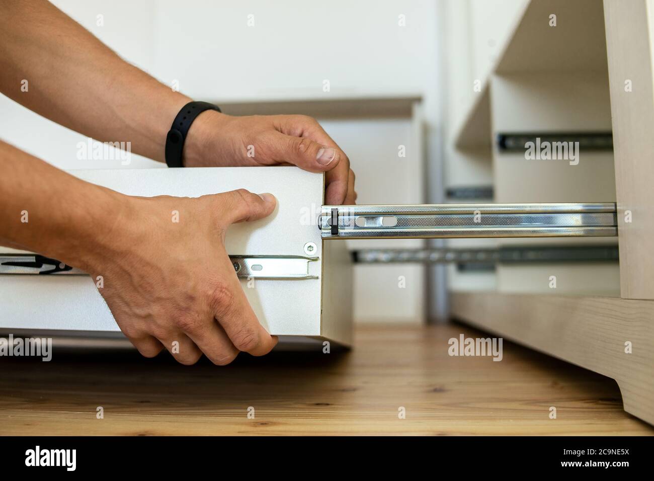 Close up of carpenter hands installing wooden drawer on sliding skids ...