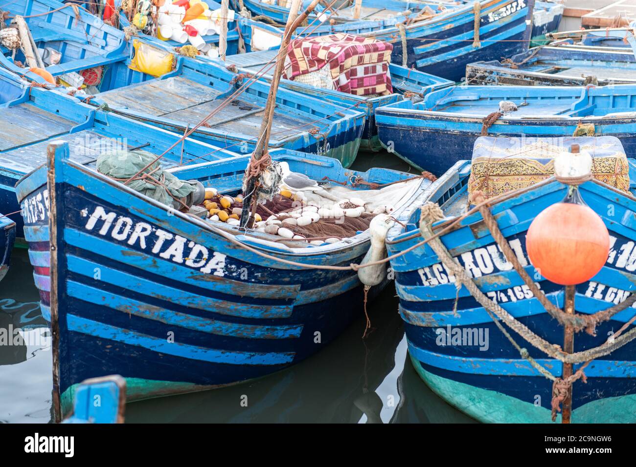 Blue wooden boats occupy the harbor in Essaouria, Morocco Stock Photo ...