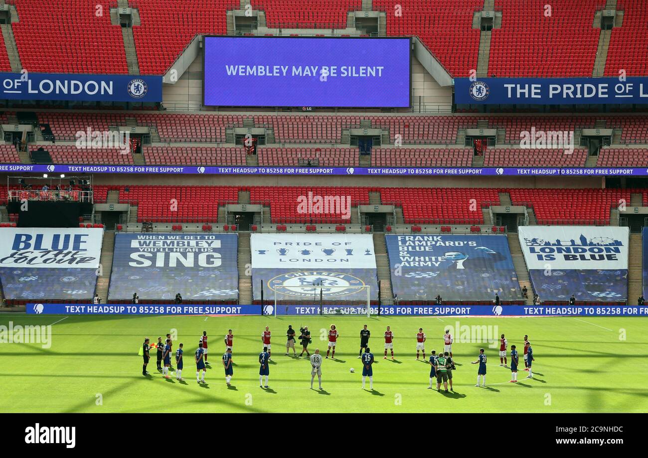 The players and match officials stand around the center-circle to ...