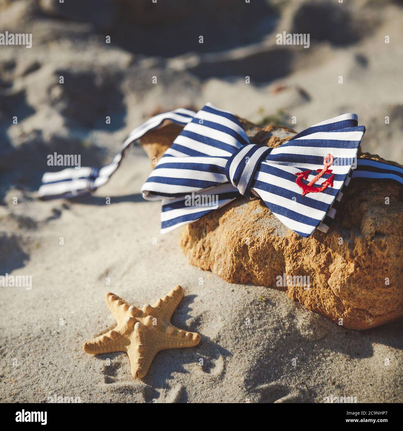 Stylish bow tie on stone at the beach. Men's and women's accessories on ...