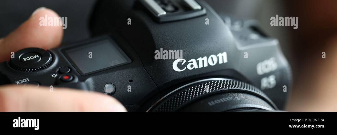 Male hand holding brand new mirrorless digital camera Canon r5 closeup ...