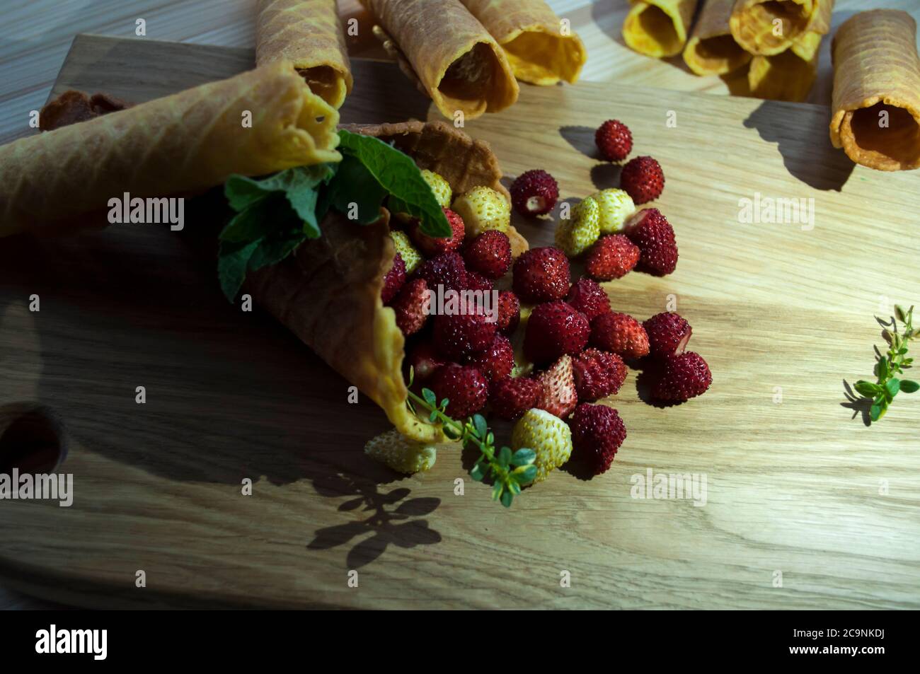 Golden waffle cone filled with strawberries and many waffle tubes ...