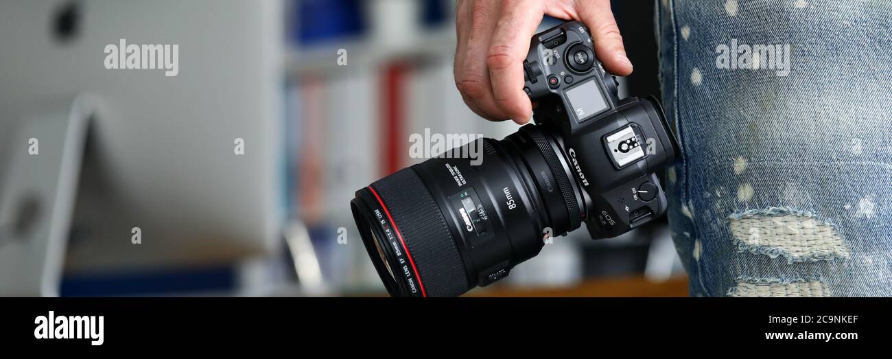Male hand holding brand new mirrorless digital camera Canon r5 closeup ...