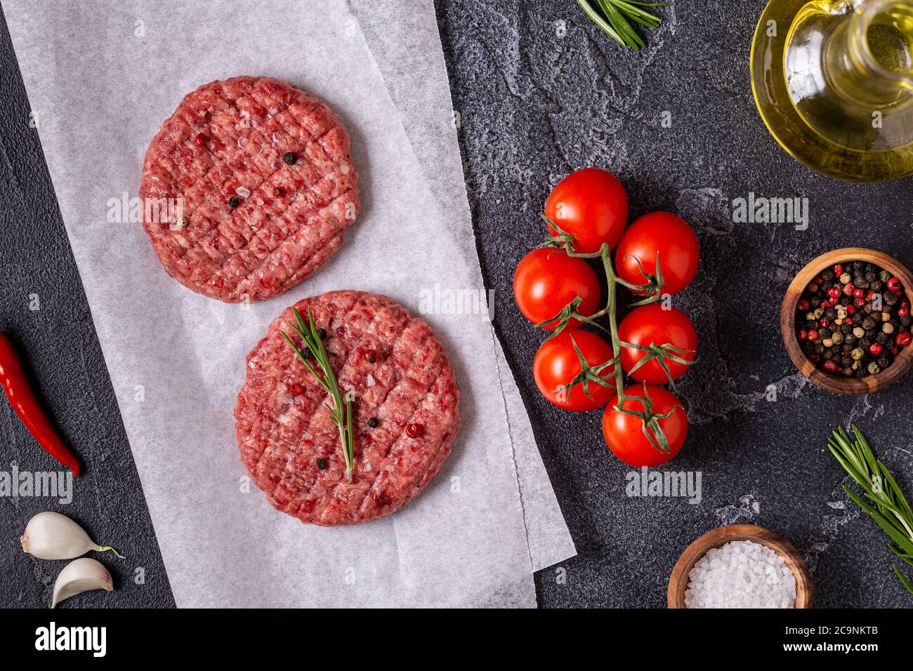 Fresh raw meat burger cutlet with herbs and spices on the black stone ...