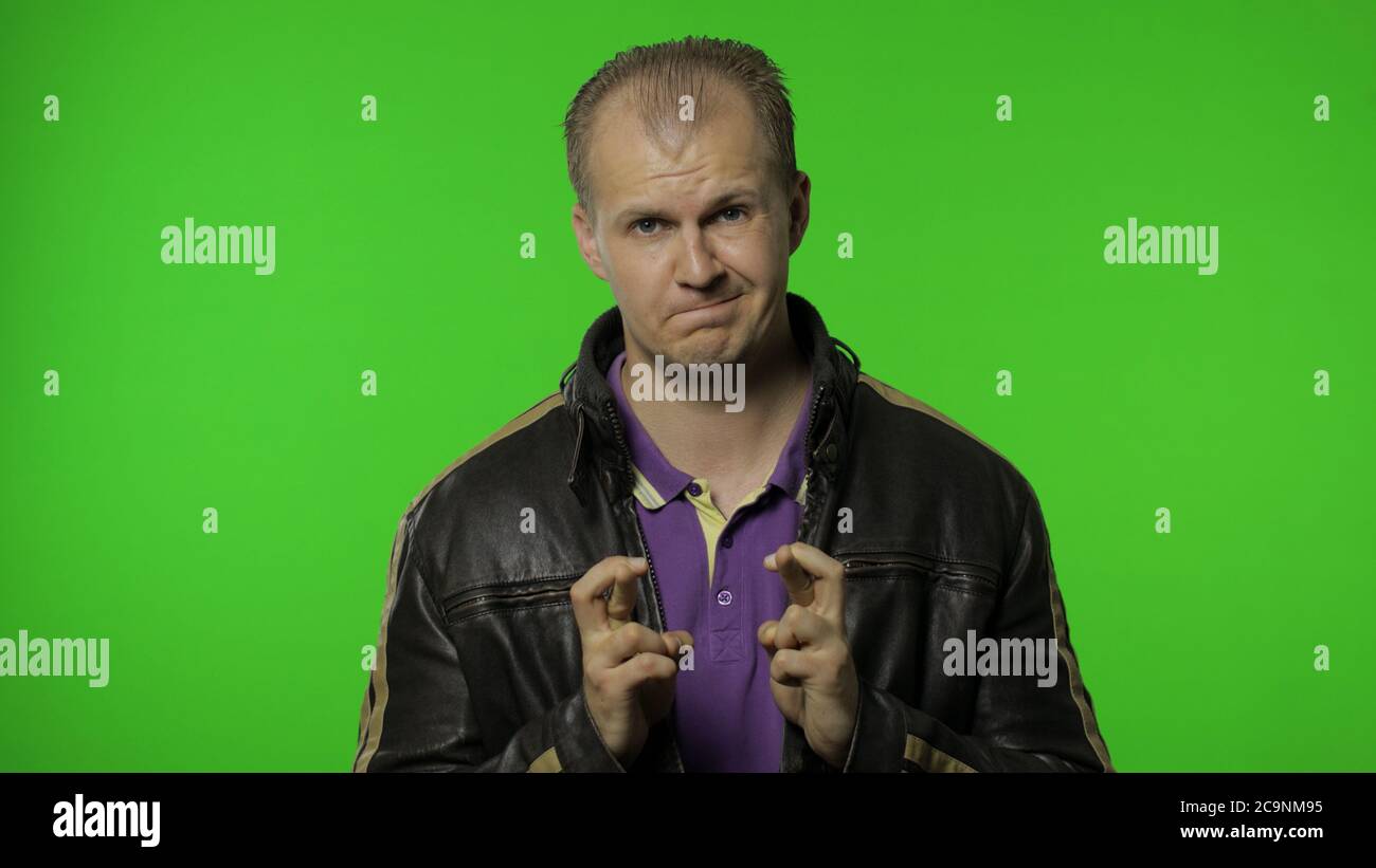 Rocker man in brown leather jacket full of hope crossing his fingers ...