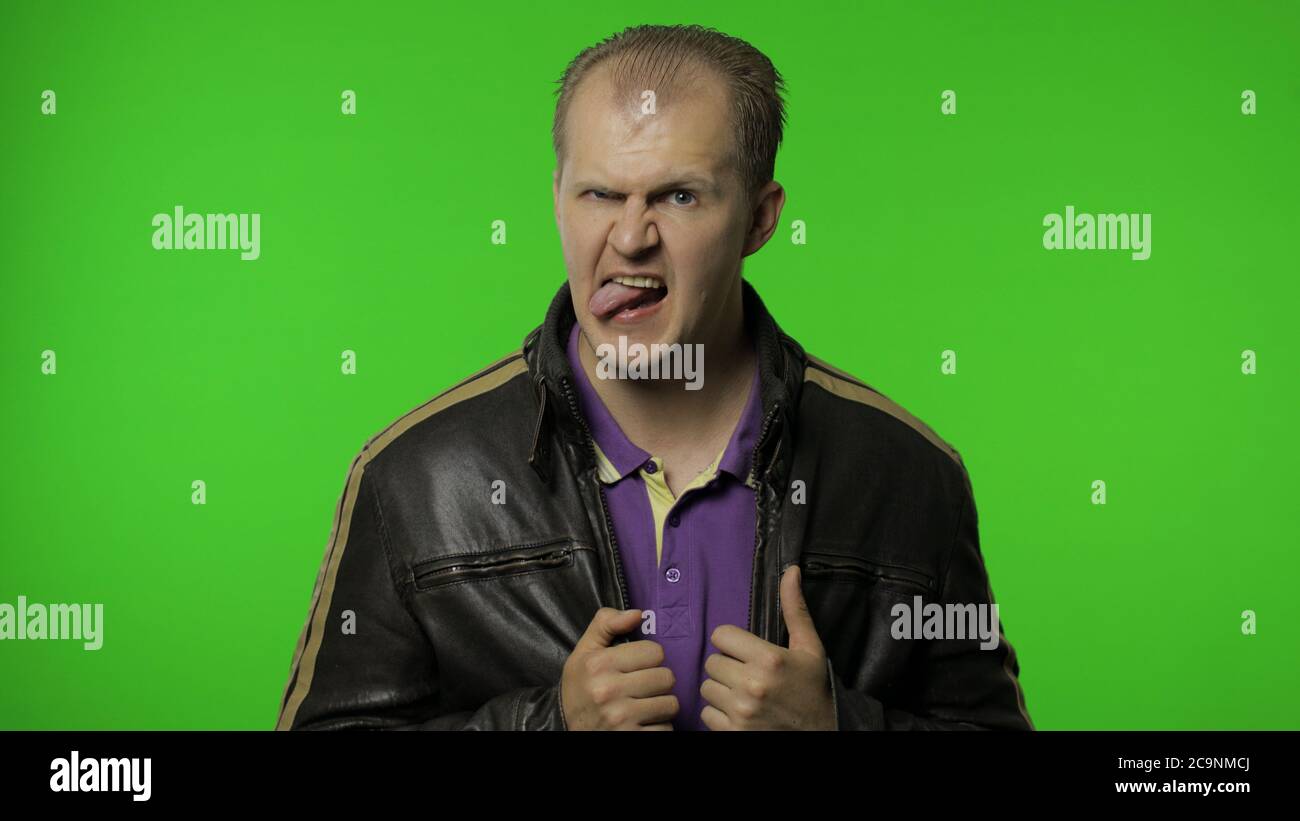 Aggressive brutal rocker man in brown leather jacket showing tongue and ...