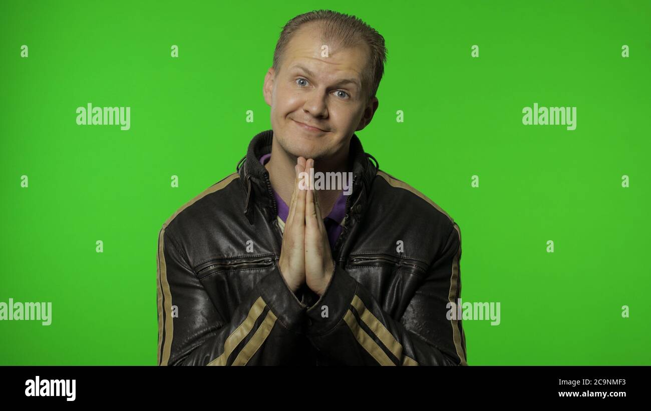 Handsome rocker man in leather jacket put hands in prayer and begging ...