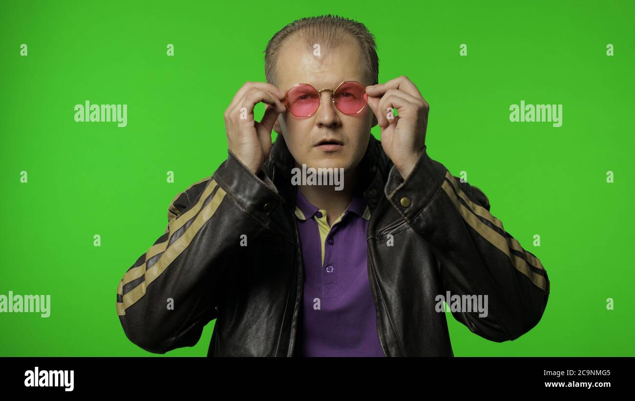 Cool brutal rocker man in brown leather jacket puts on pink sunglasses ...