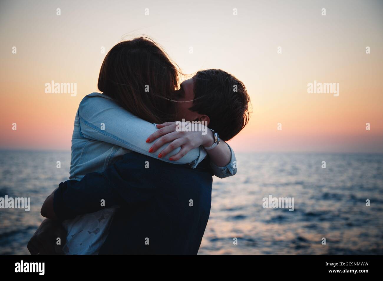Close up of young couple hugging at sunrise beach background, summer ...