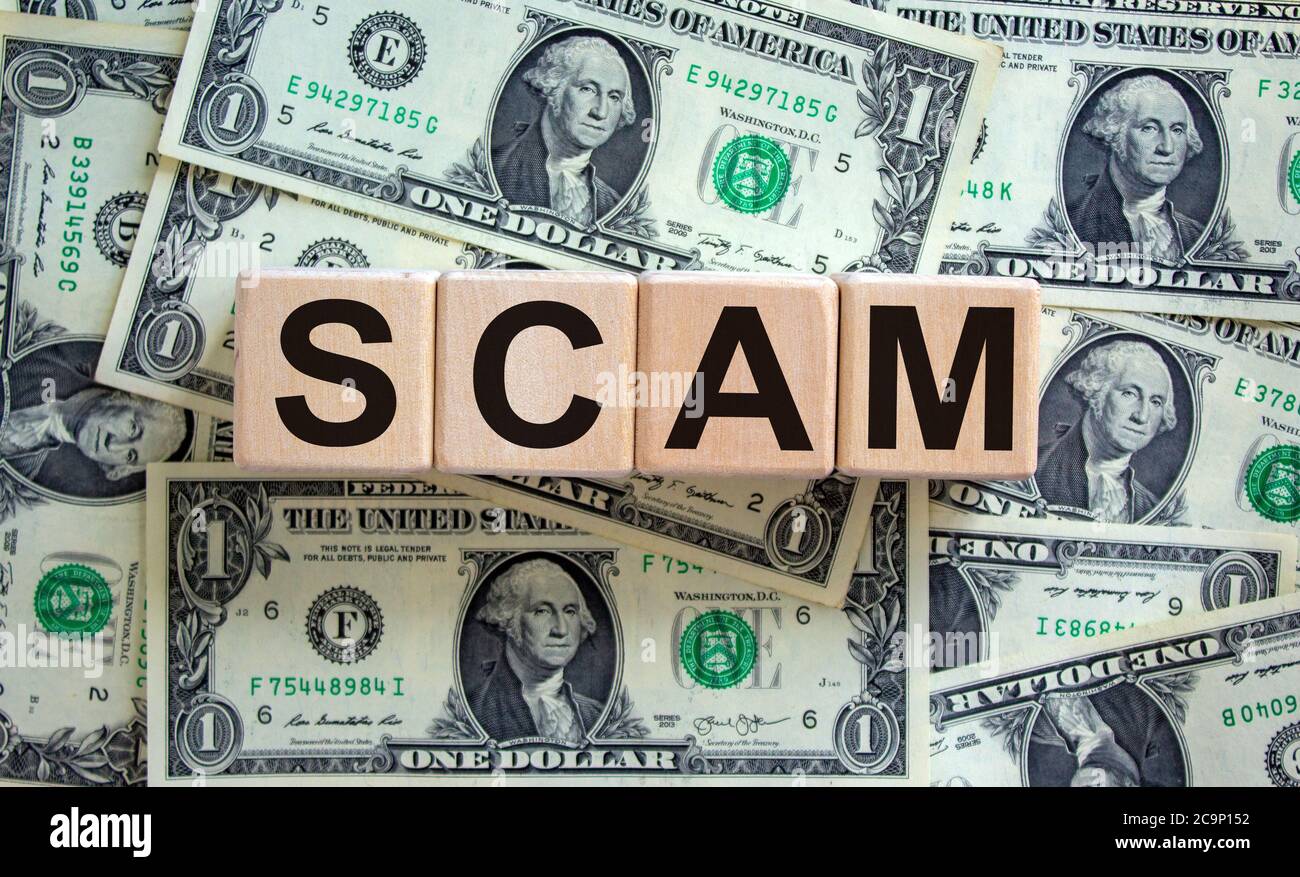 Wood cubes with word 'scam' on beautiful background from dollar bills ...