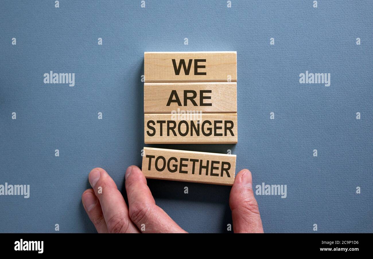 Wooden blocks form the words 'we are stronger together' on blue ...