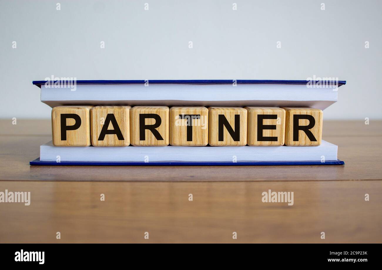 Concept word 'partner' on wooden cubes between pages of a book on a ...