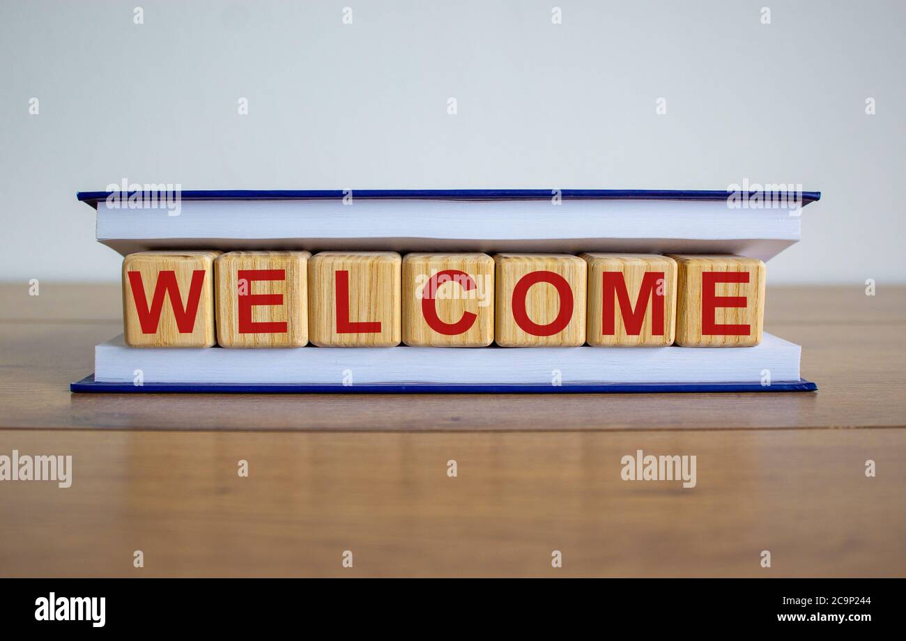 Concept word 'welcome' on wooden circles between pages of a book on a ...