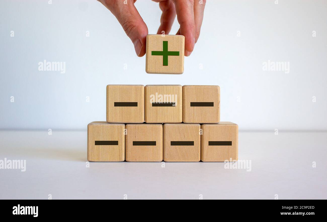 Male hand placing a cube with plus sign on top of a pyramid with minus ...