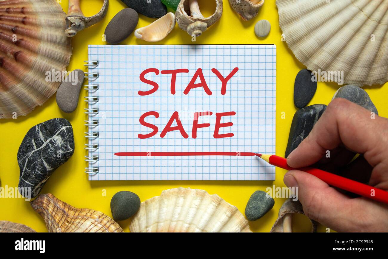 Male hand with red pencil writing 'stay safe' on white note. Beautiful ...