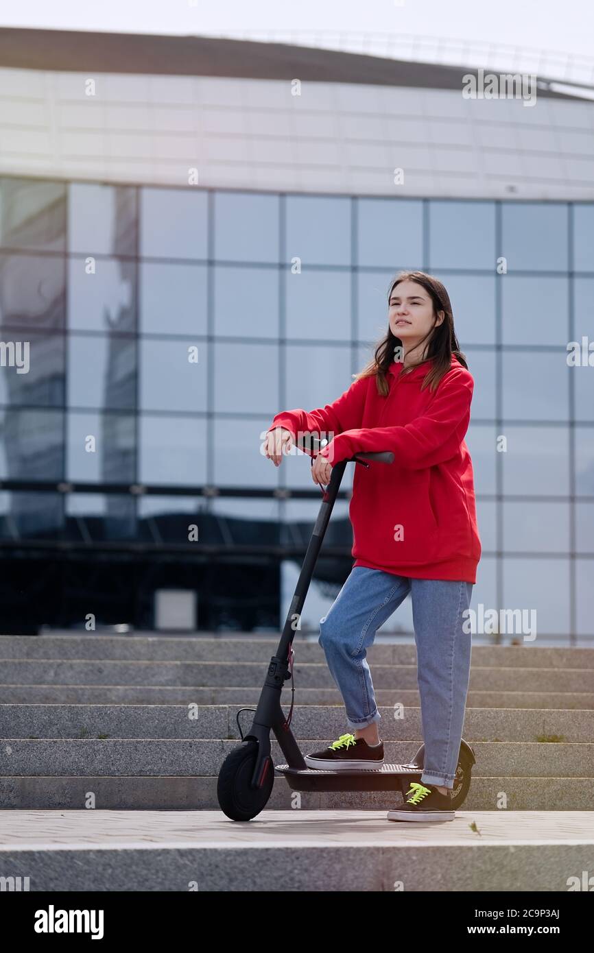 Cute teenager girl riding electric kick scooter in a cityscape Stock ...