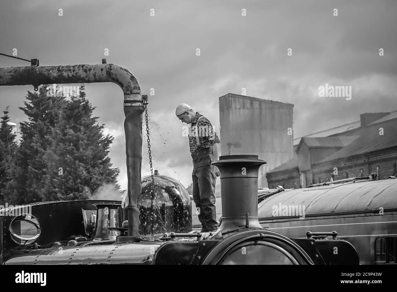 Steam train crew fireman filling water tank of vintage steam locomotive ...