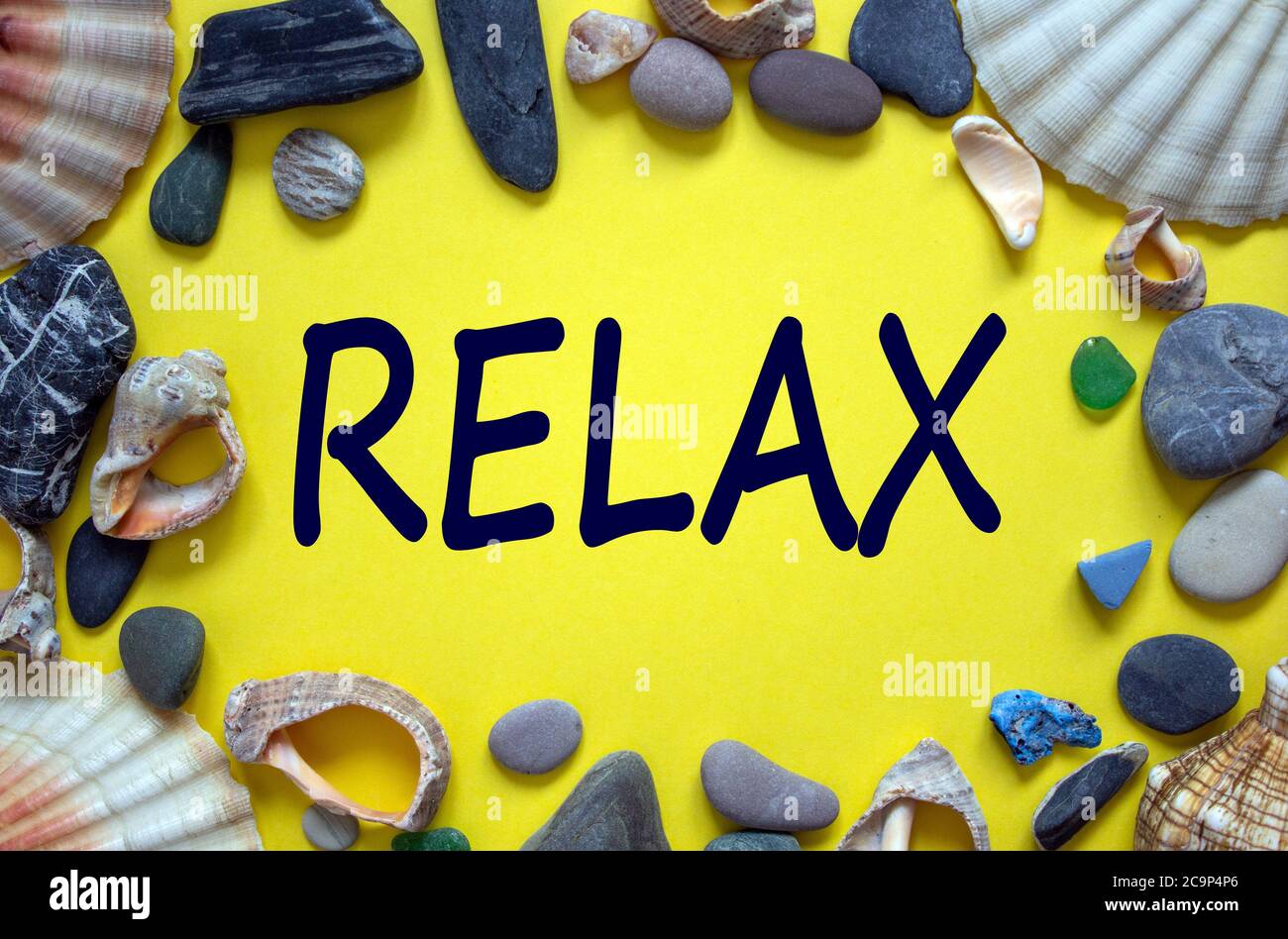 Word 'relax' on a beautiful yellow background. Sea stones and seashells ...