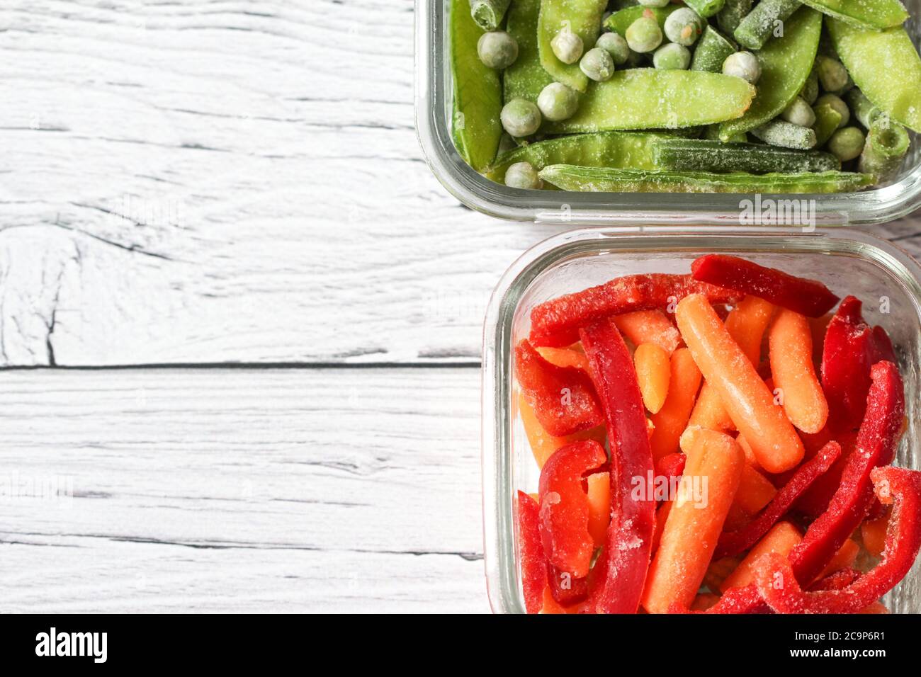Frozen vegetables in the transparent bowls on the concrete wooden ...