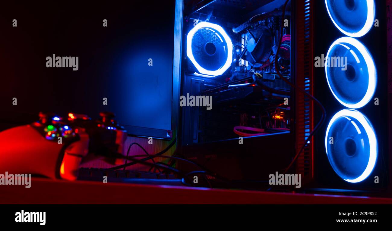 Glass pc case with blue lighting with a game pad on the foreground ...