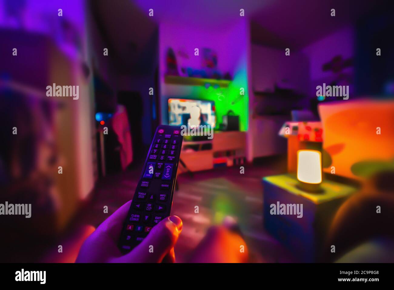 Man watching tv in a colorful living room at night Stock Photo - Alamy