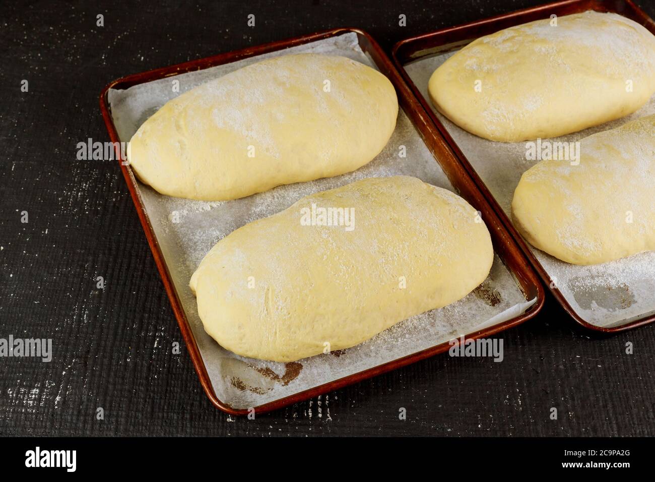 Four uncooked bread in pan ready for baking Stock Photo - Alamy