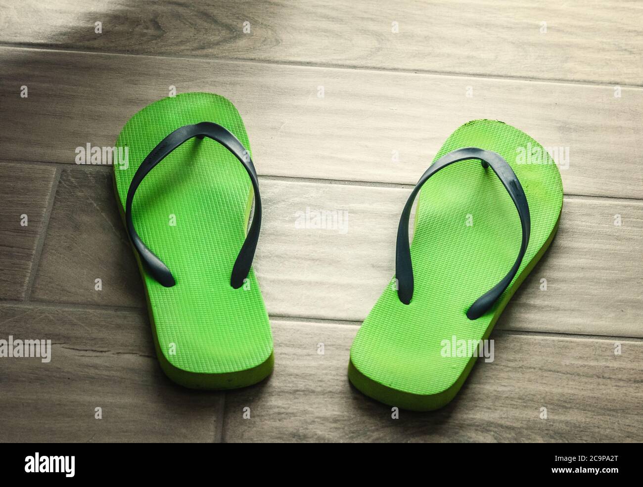 Detail of green flip flops on a grey floor Stock Photo - Alamy