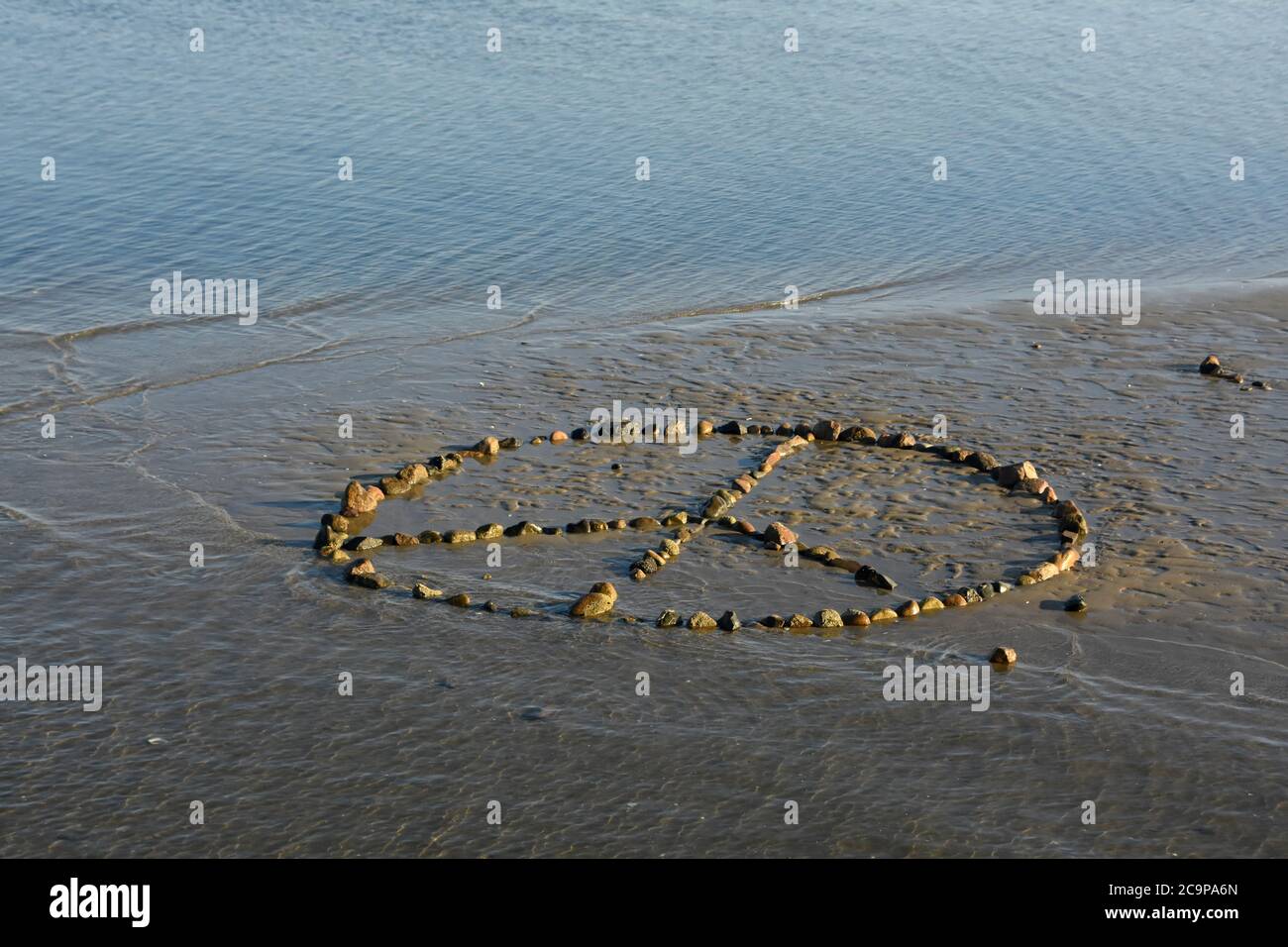 Shallow water around a peace sign made of rocks Stock Photo - Alamy