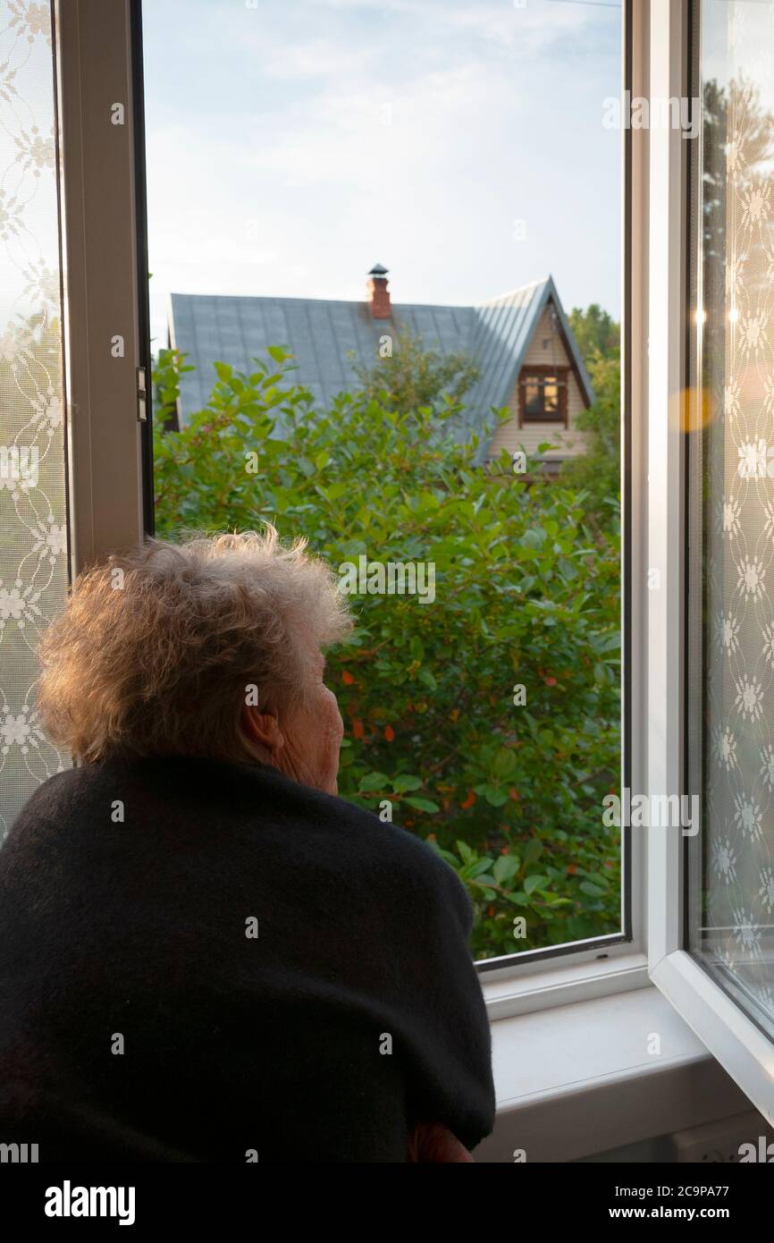 senior woman looking out open window of country house Stock Photo - Alamy