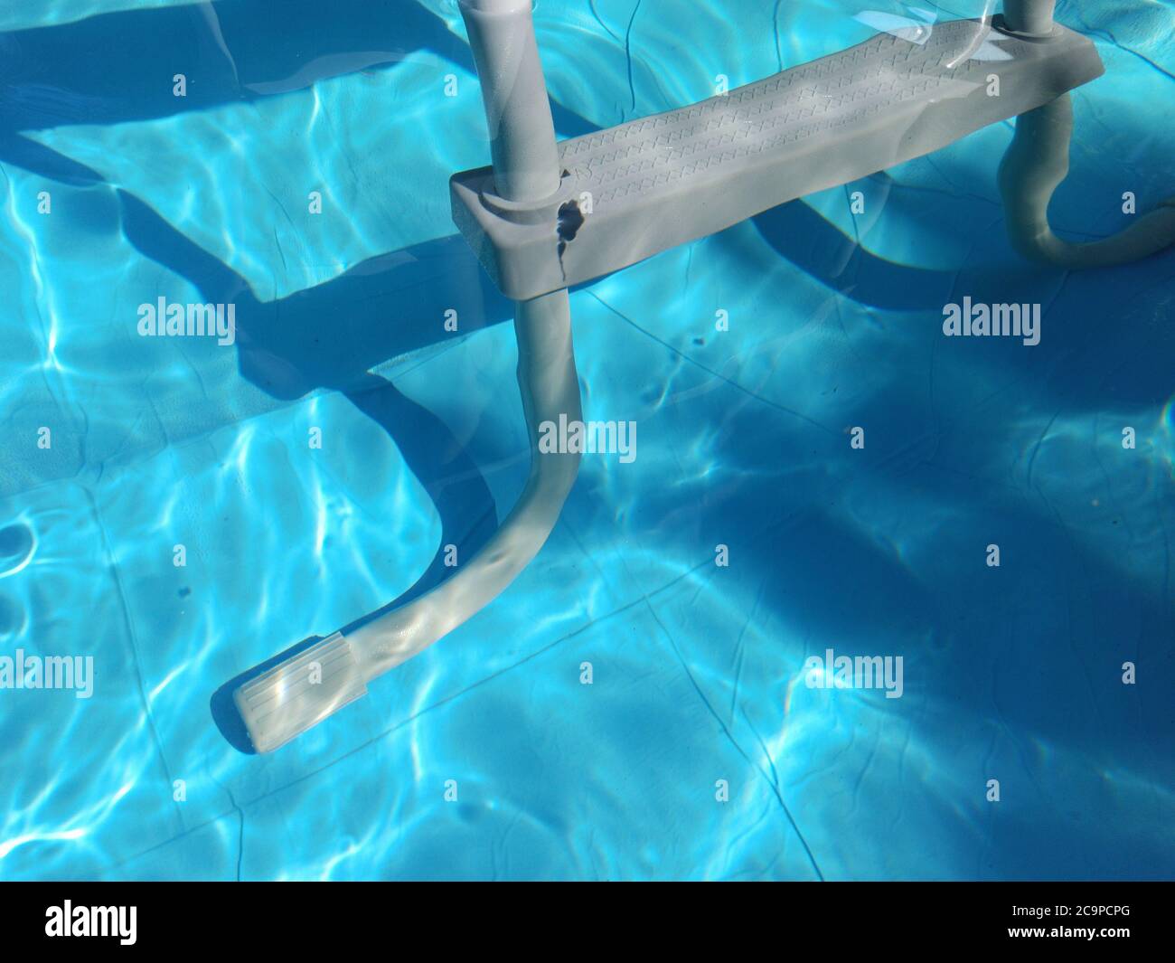 Close up of a grey pool ladder in a modern swimming pool in summertime ...