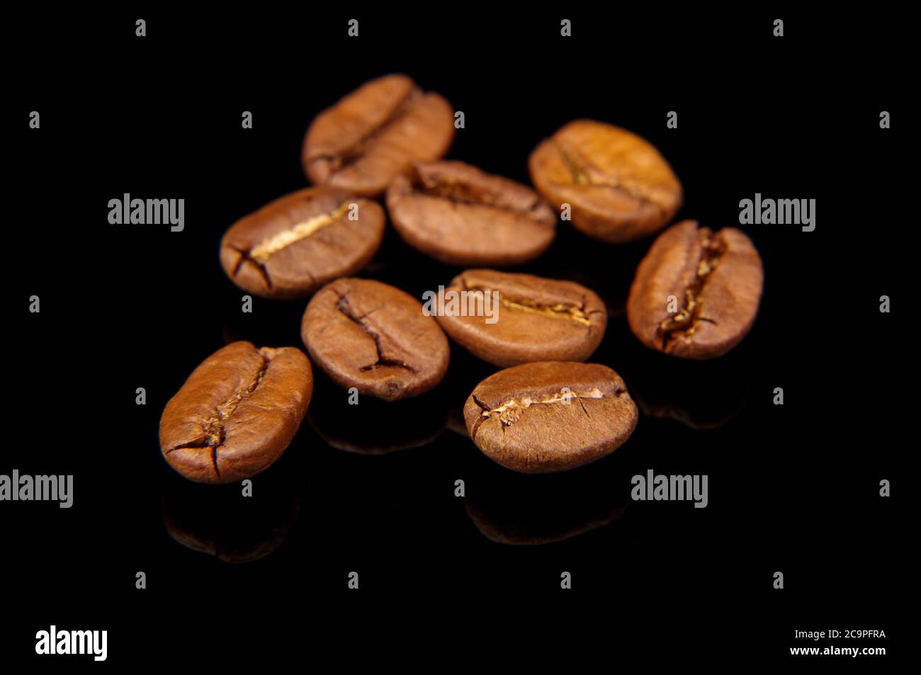 Coffee beans macro close up isolated on the black reflective background ...