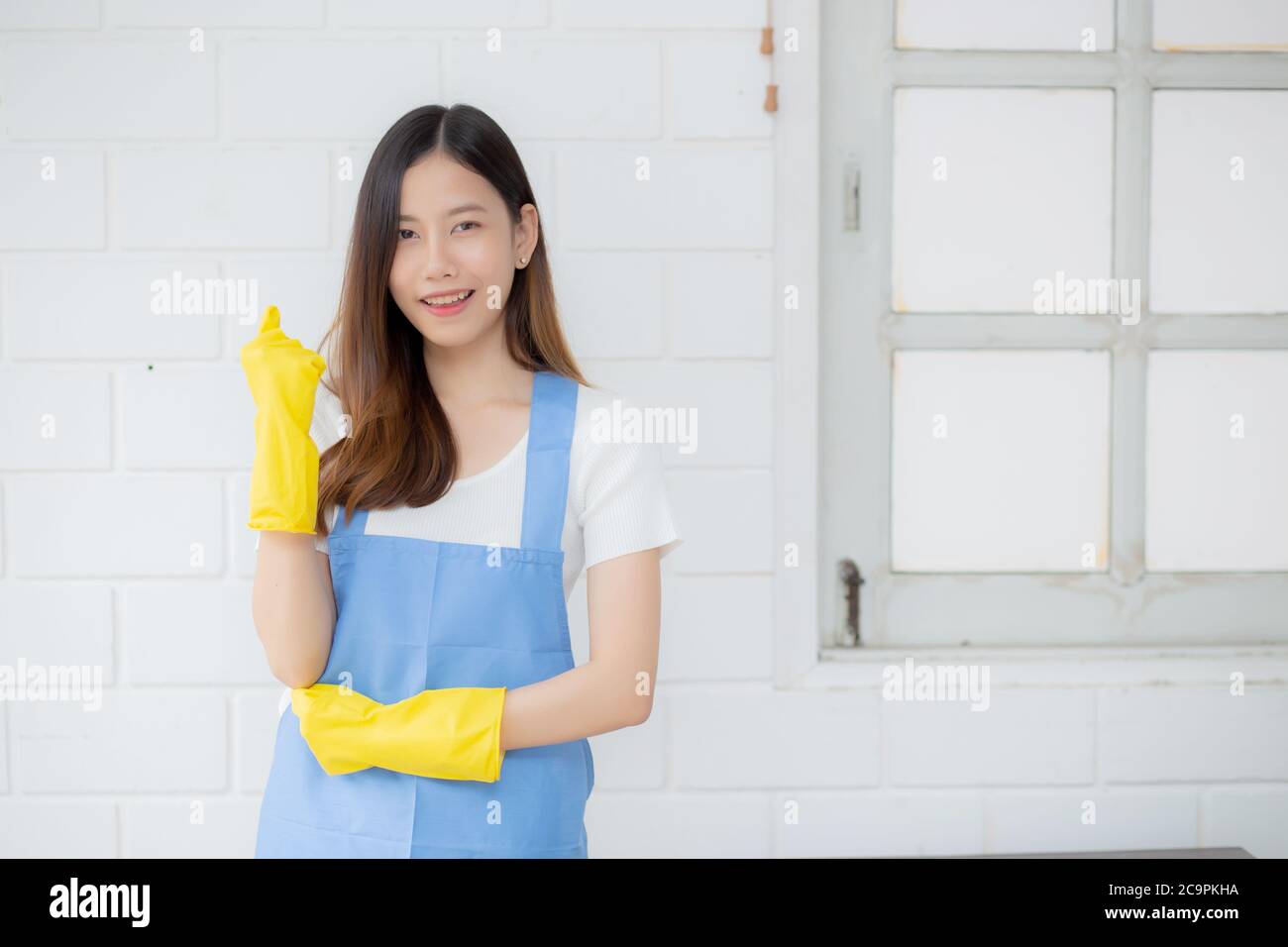 Portrait young asian woman is housekeeper in rubber gloves and apron ...