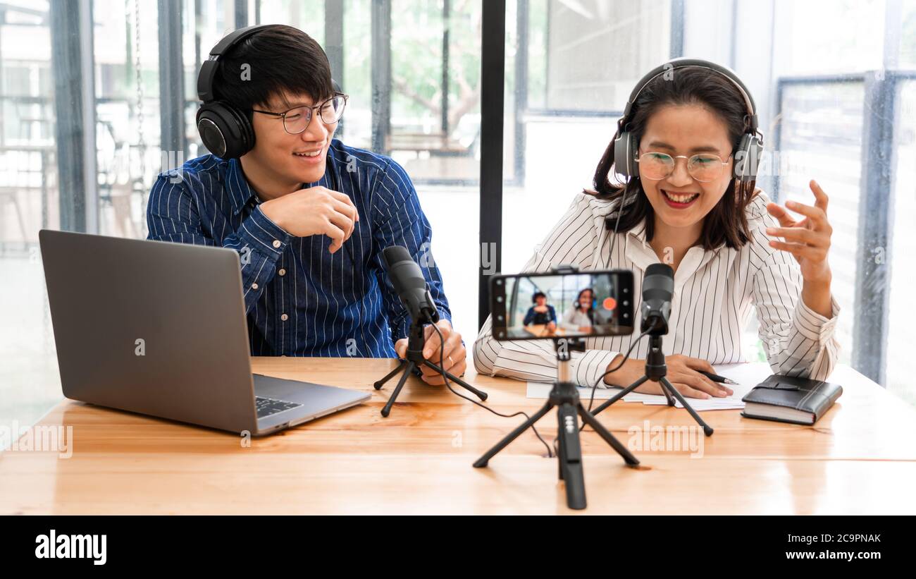 Asian Man and woman podcasters in headphones recording content with ...