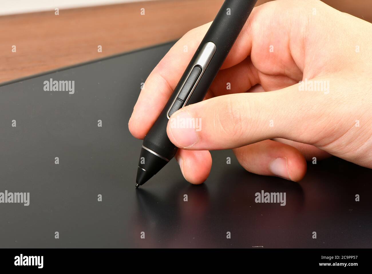 Hand of the designer with a pen on a tablet. Isolated on wood ...