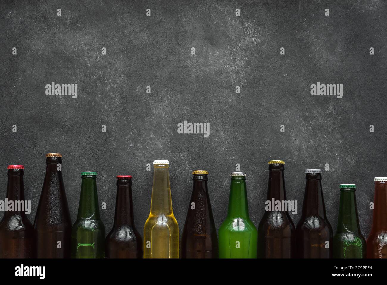 Assortment of beer bottles on black background, top view, copy space ...