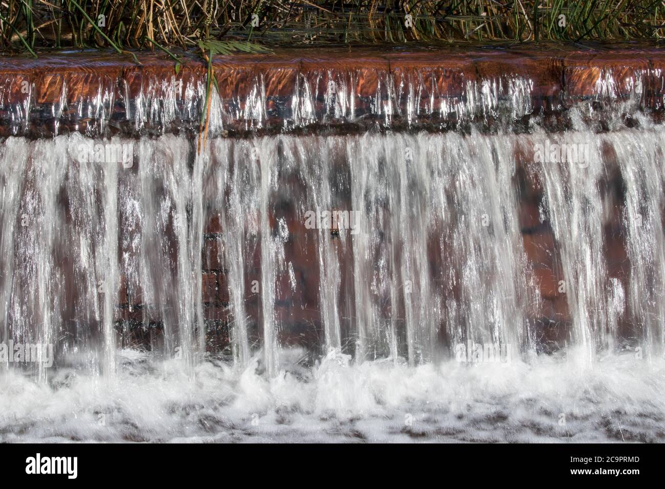 Water flowing over flooded weir Stock Photo - Alamy