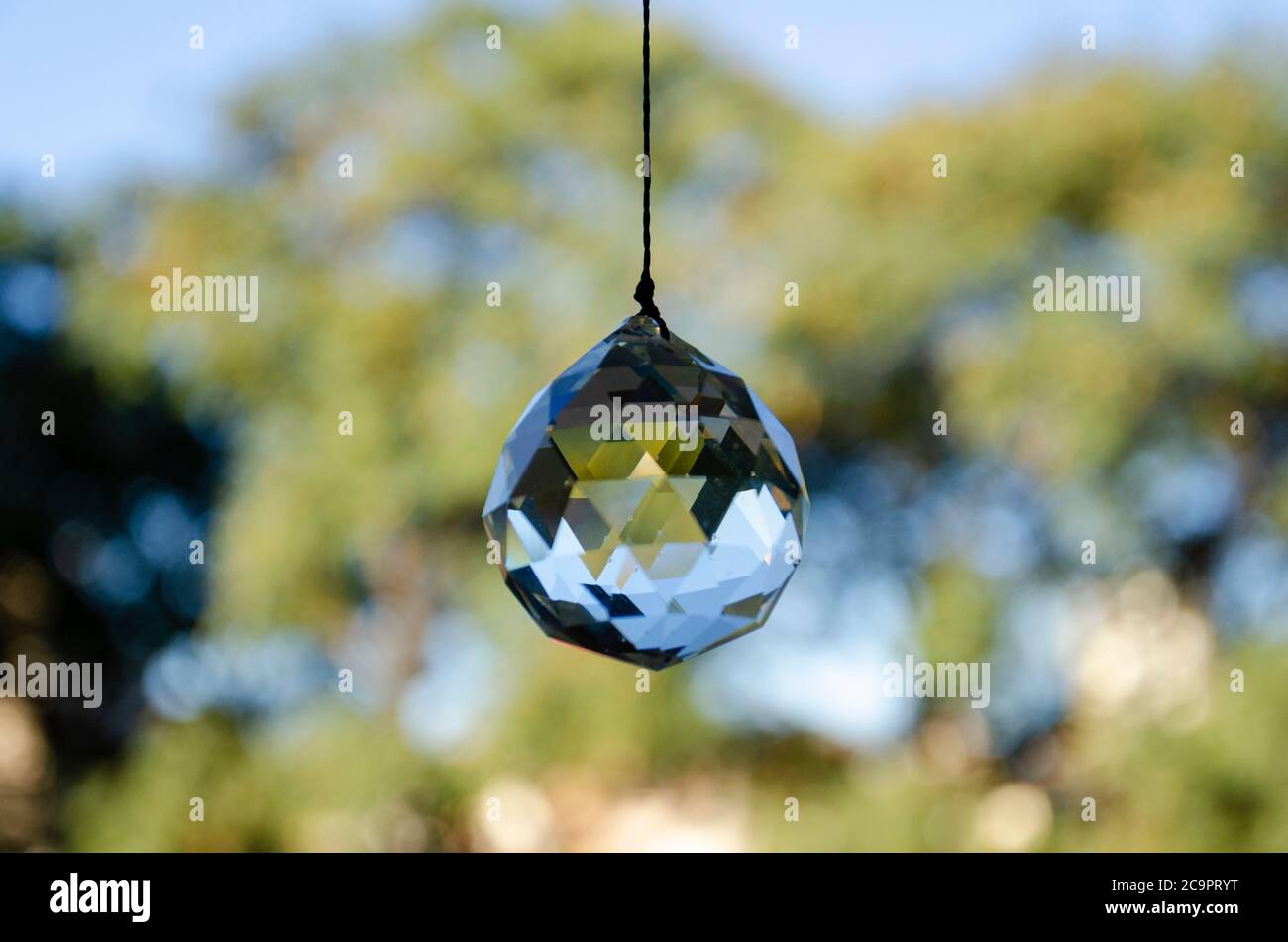 Feng Shui glass ball hanging in a window with the sky in the background ...