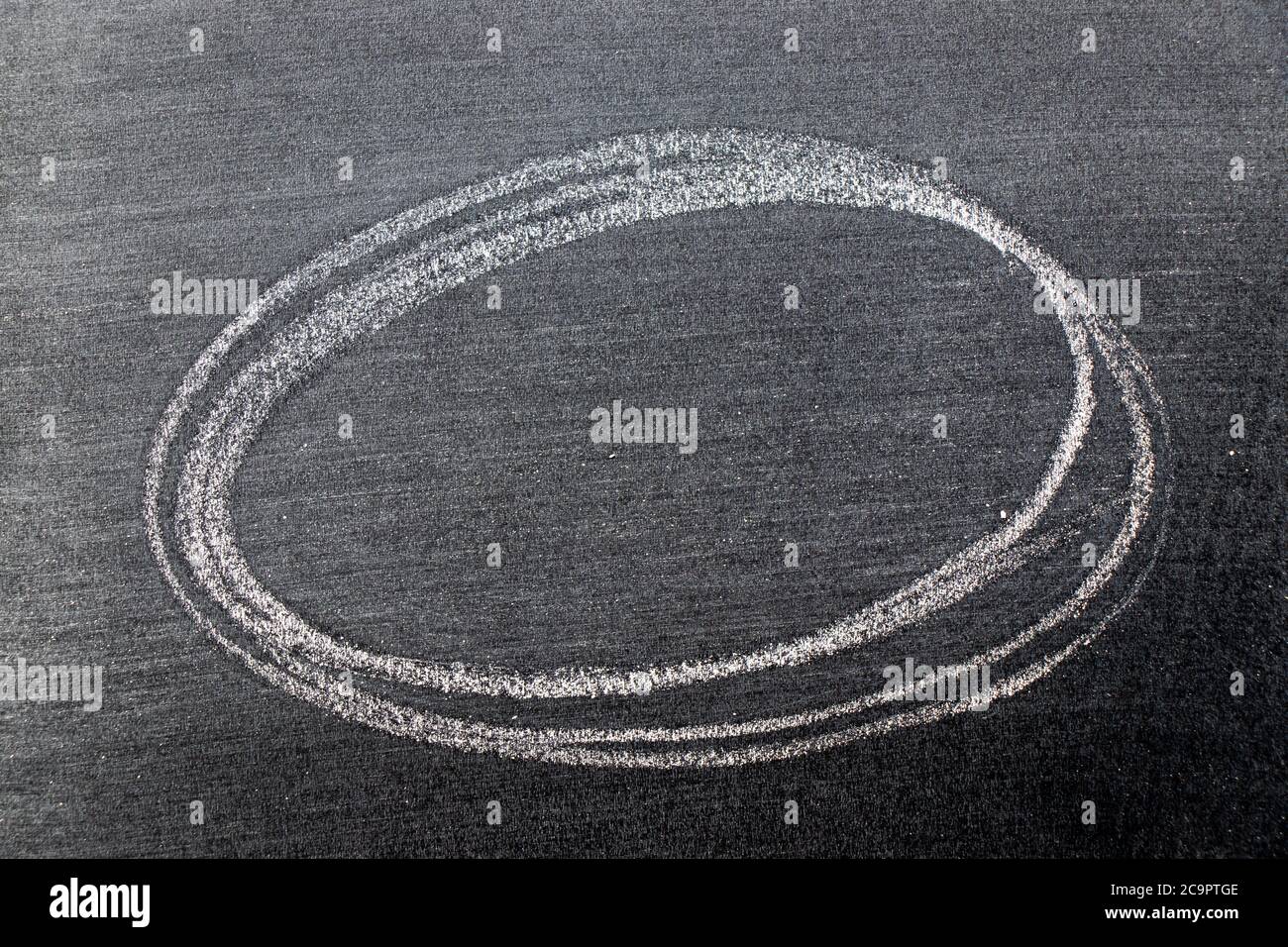White color chalk hand drawing in circle or oval shape on black board ...