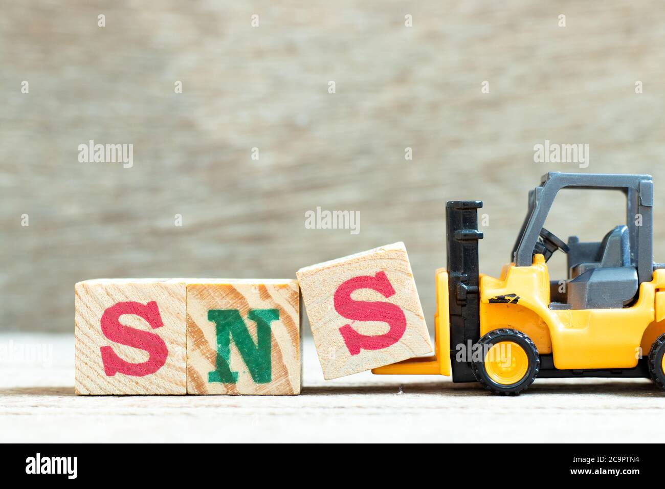 Toy forklift hold letter block S to complete word SNS (abbreviation of ...