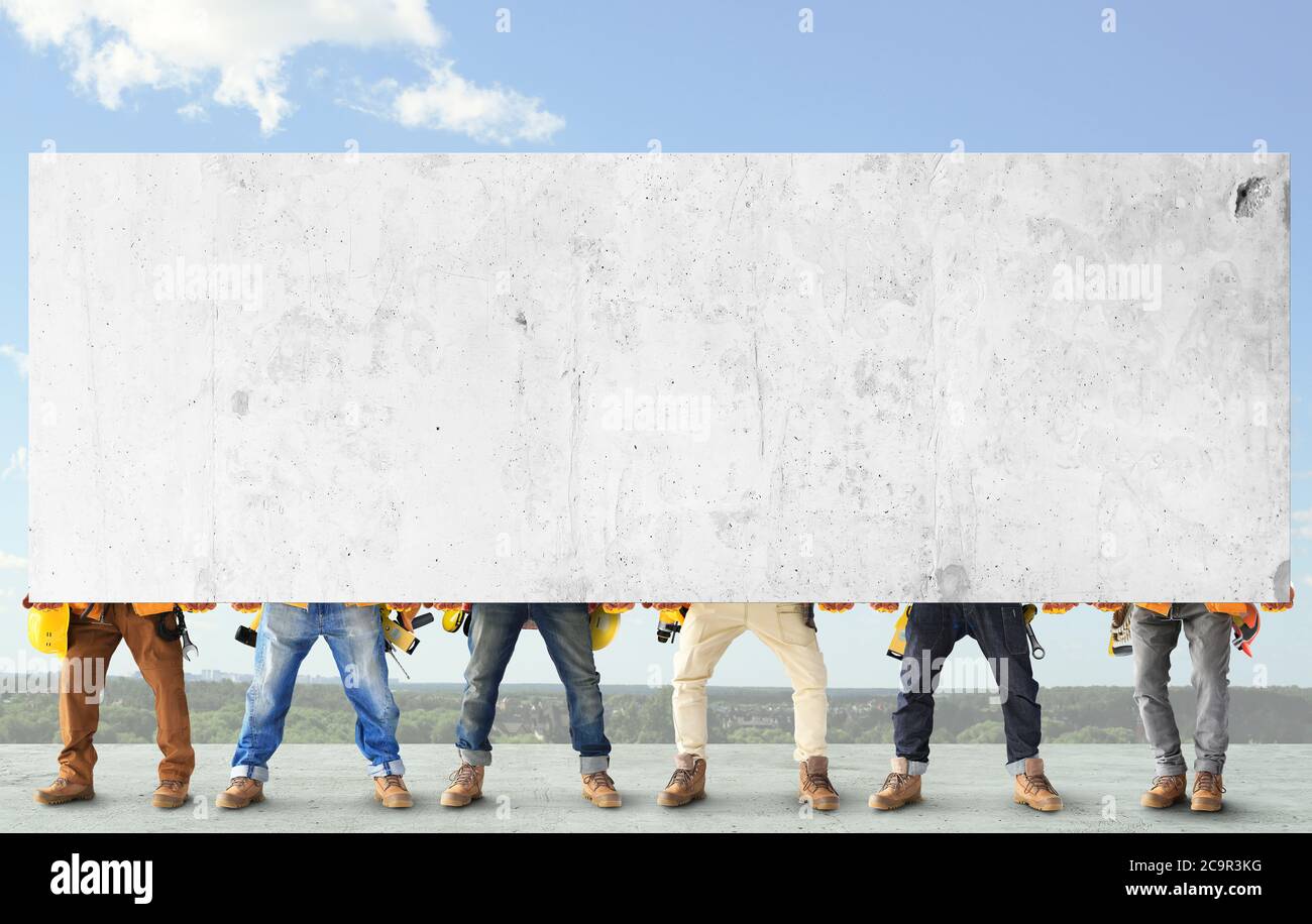 Builders with tools in construction clothing hold a heavy slab Stock ...
